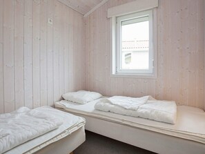 Quarto com duas camas, janela e paredes de madeira.