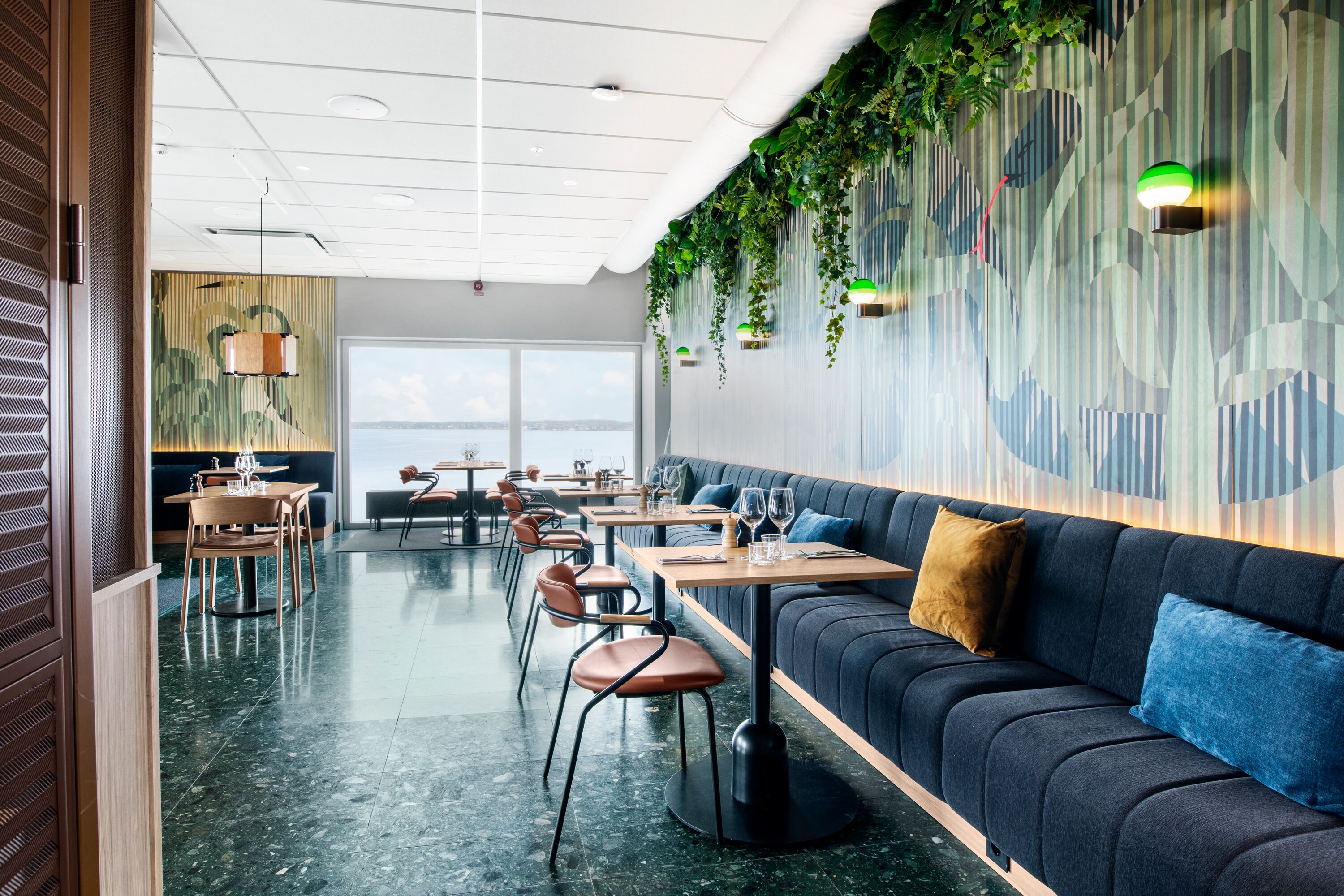 Um restaurante moderno com um balcão extenso, área de estar e grandes janelas com vista.