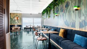 Um restaurante moderno com um balcão extenso, área de estar e grandes janelas com vista.