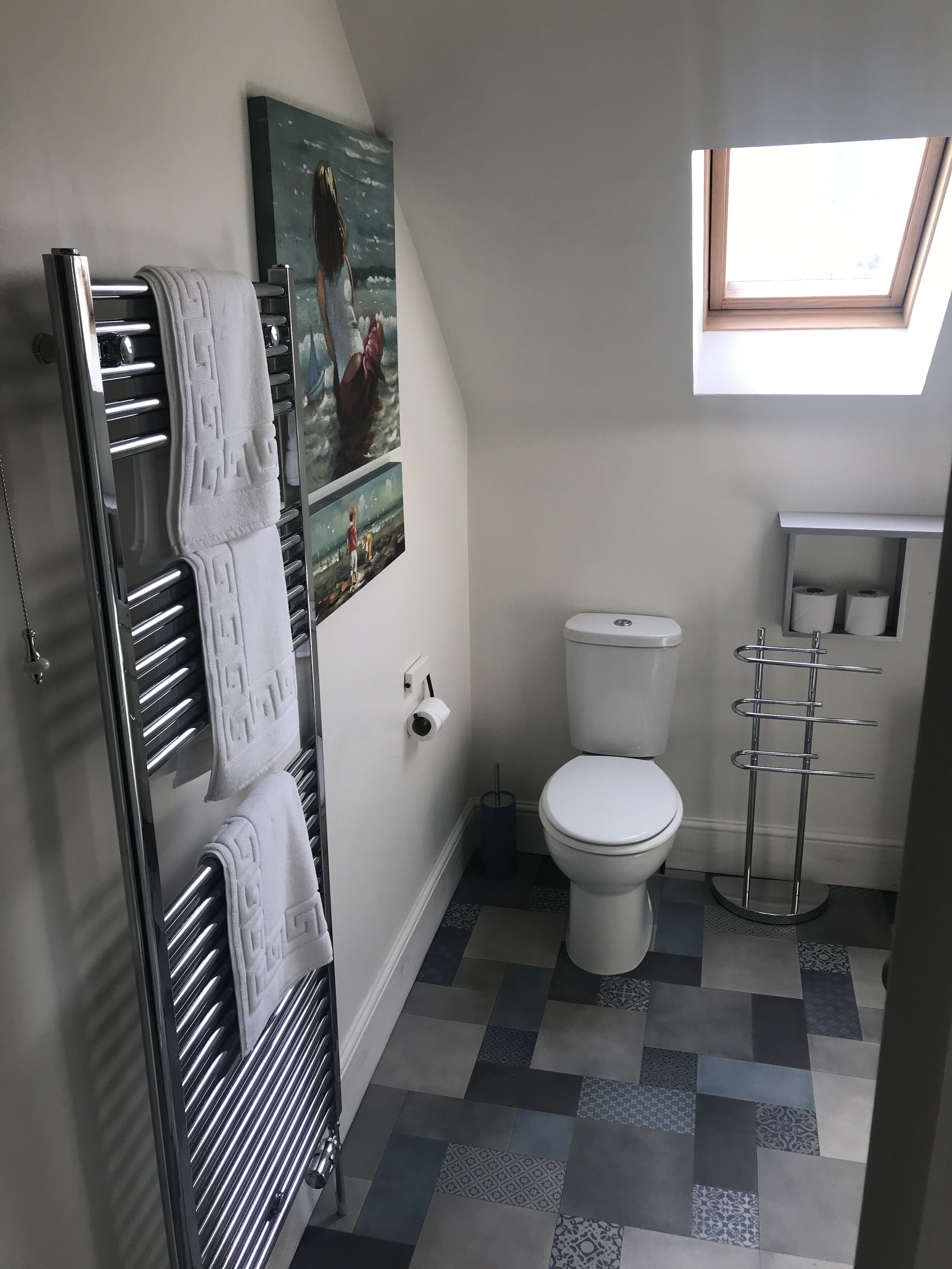 Casa de banho com design moderno, incluindo sanita, porta-toalhas e janela.