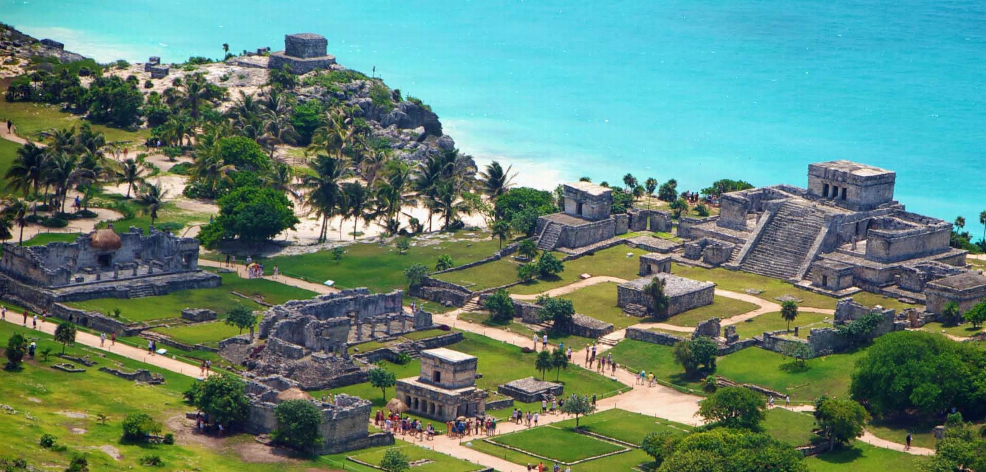Uma antiga cidade Maia com estruturas de pedra e uma praia.