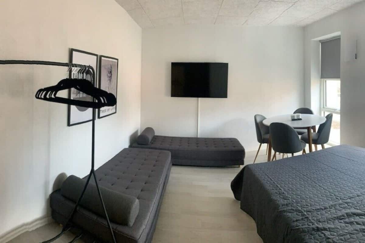 Quarto moderno com cama, sofá, escrivaninha e televisão.