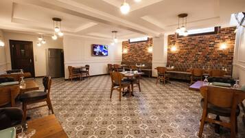 Uma sala de jantar com piso estampado, móveis de madeira e detalhes em tijolo.