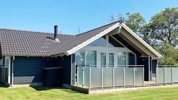 Uma casa moderna com telhado inclinado, janelas grandes e varanda coberta.