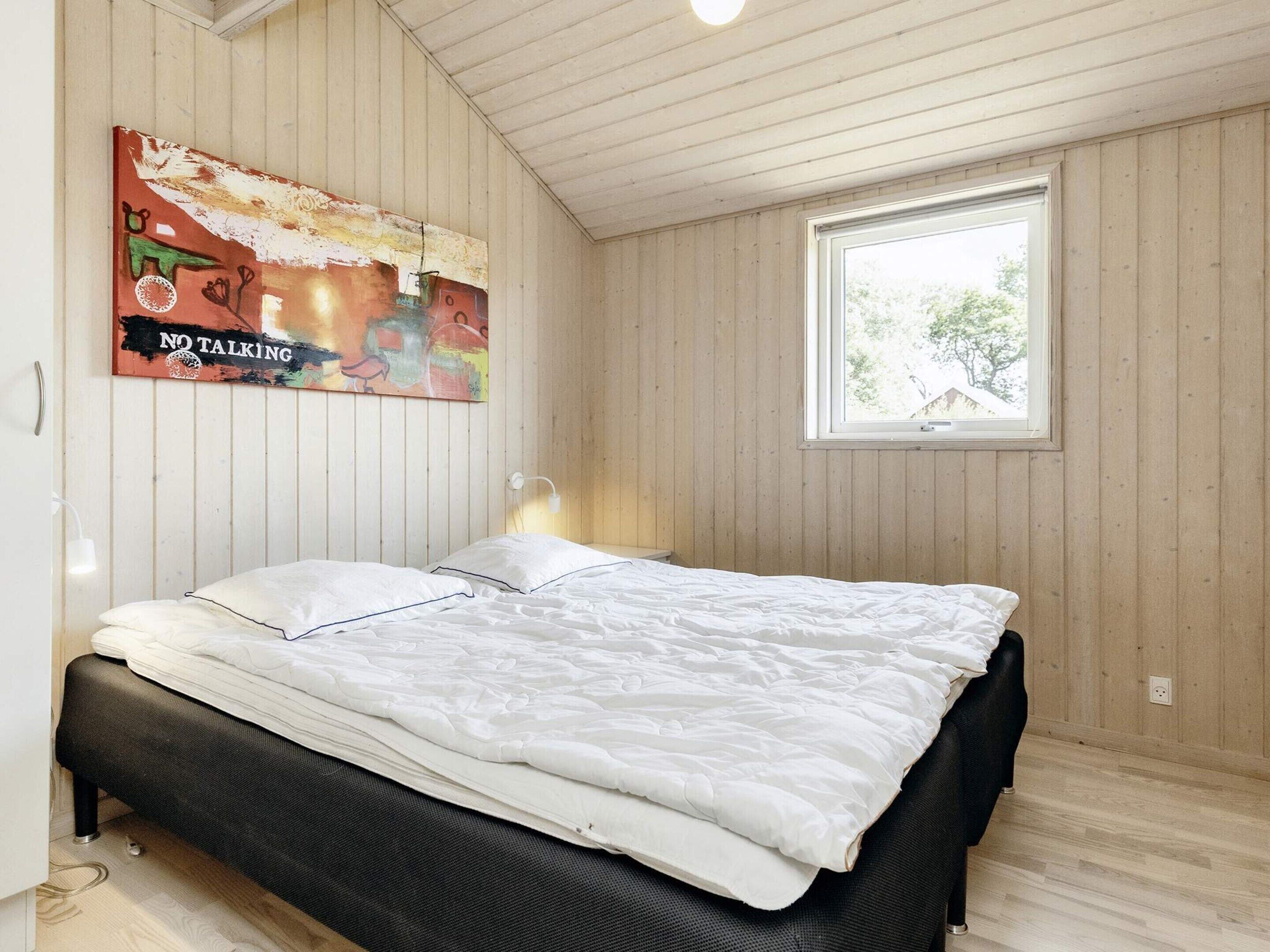 Quarto com uma cama, janela e uma obra de arte na parede.