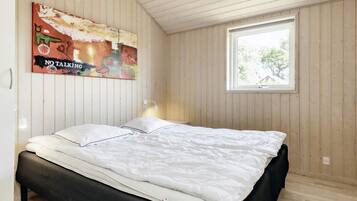Quarto com uma cama, janela e uma obra de arte na parede.
