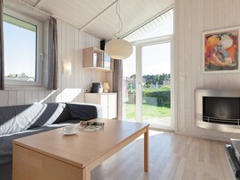 Uma sala de estar moderna com um sofá, uma mesa de centro, uma lareira e uma janela grande com cortinas.
