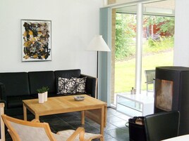 Sala de estar com sofá, mesa e TV. Janela com vista para o verde lá fora.