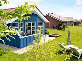 Uma casa azul com varanda, um pequeno jardim e área de recreação.
