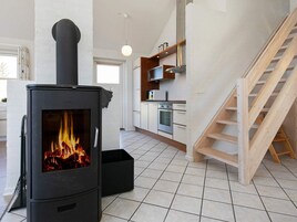 Cozinha moderna com lareira a lenha, armários brancos e escada de madeira.