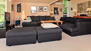 Uma sala de estar moderna com sofá seccional, pufes, uma mesa de centro e uma televisão.