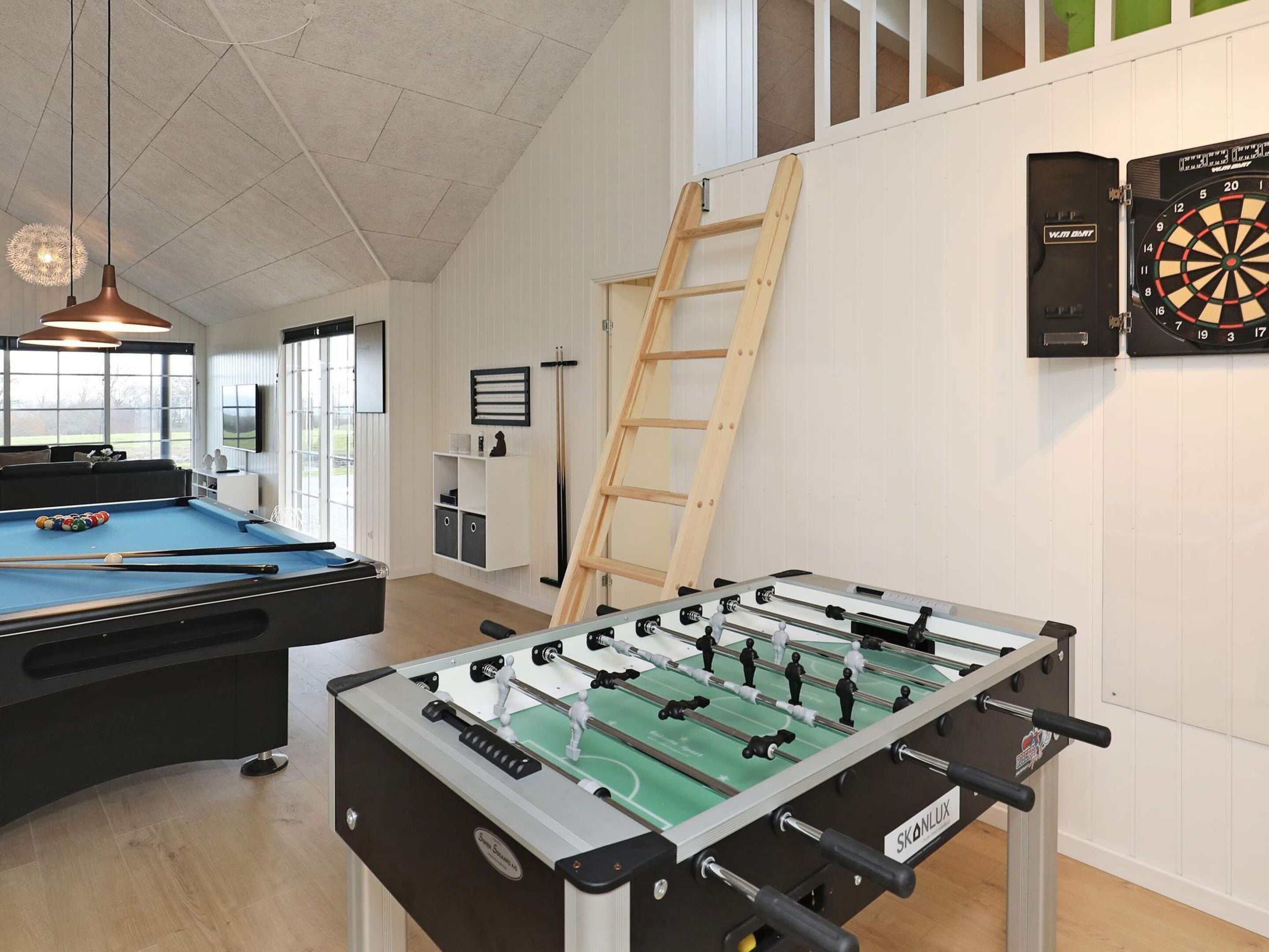 Quarto com mesa de pebolim, mesa de bilhar e dardos.