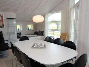 Uma sala de jantar com uma mesa branca, cadeiras pretas e um lustre.