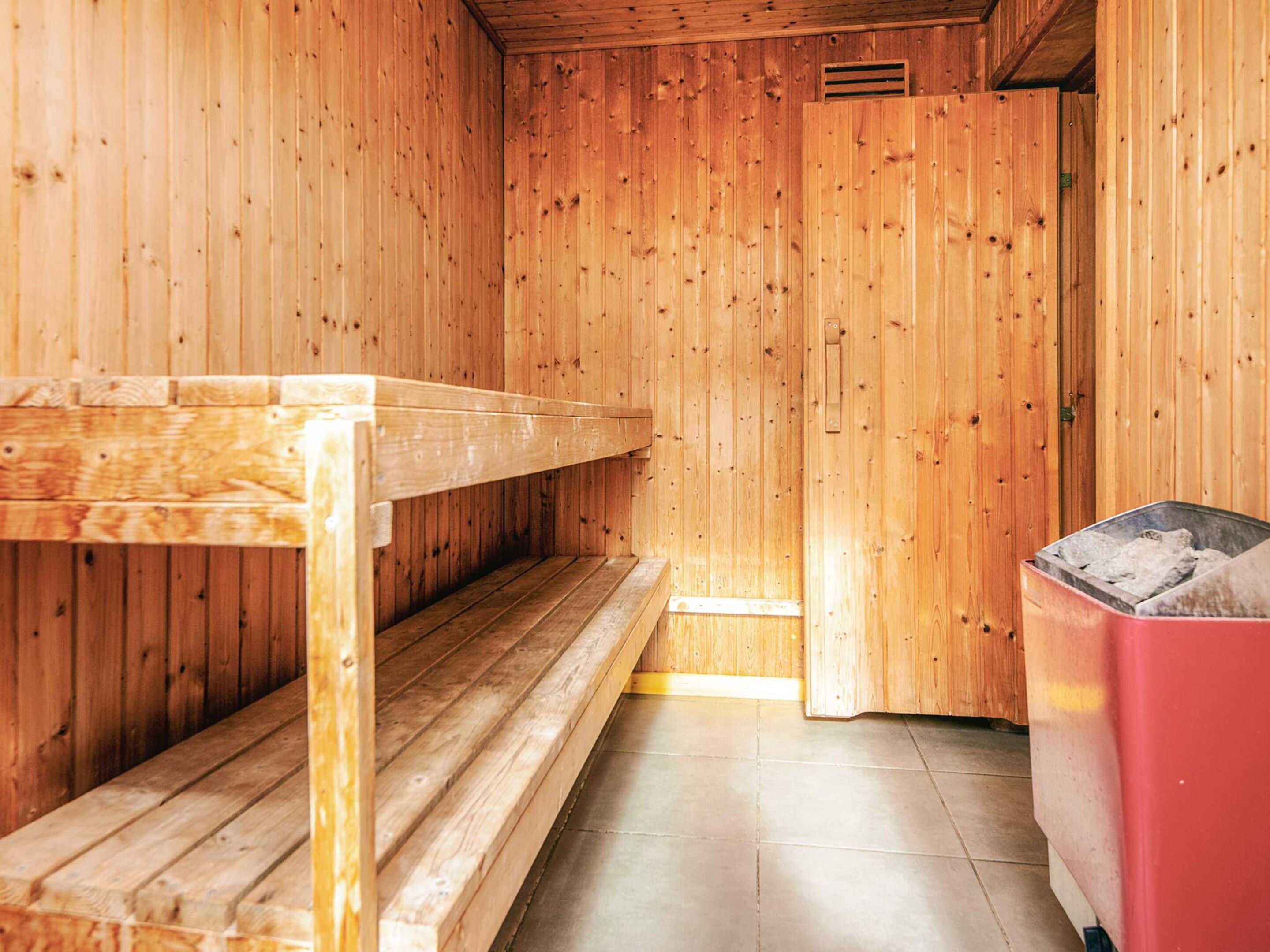 Uma sala de sauna de madeira com bancos e um banco com toalha.