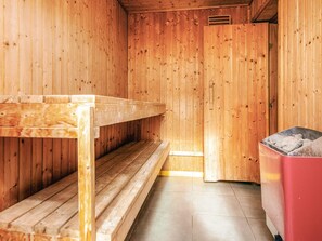 Uma sala de sauna de madeira com bancos e um banco com toalha.