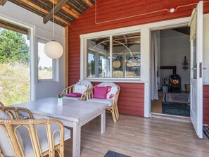 Um quarto acolhedor com uma mesa de madeira, cadeiras de vime, uma janela com vista e uma porta que dá para outra área.