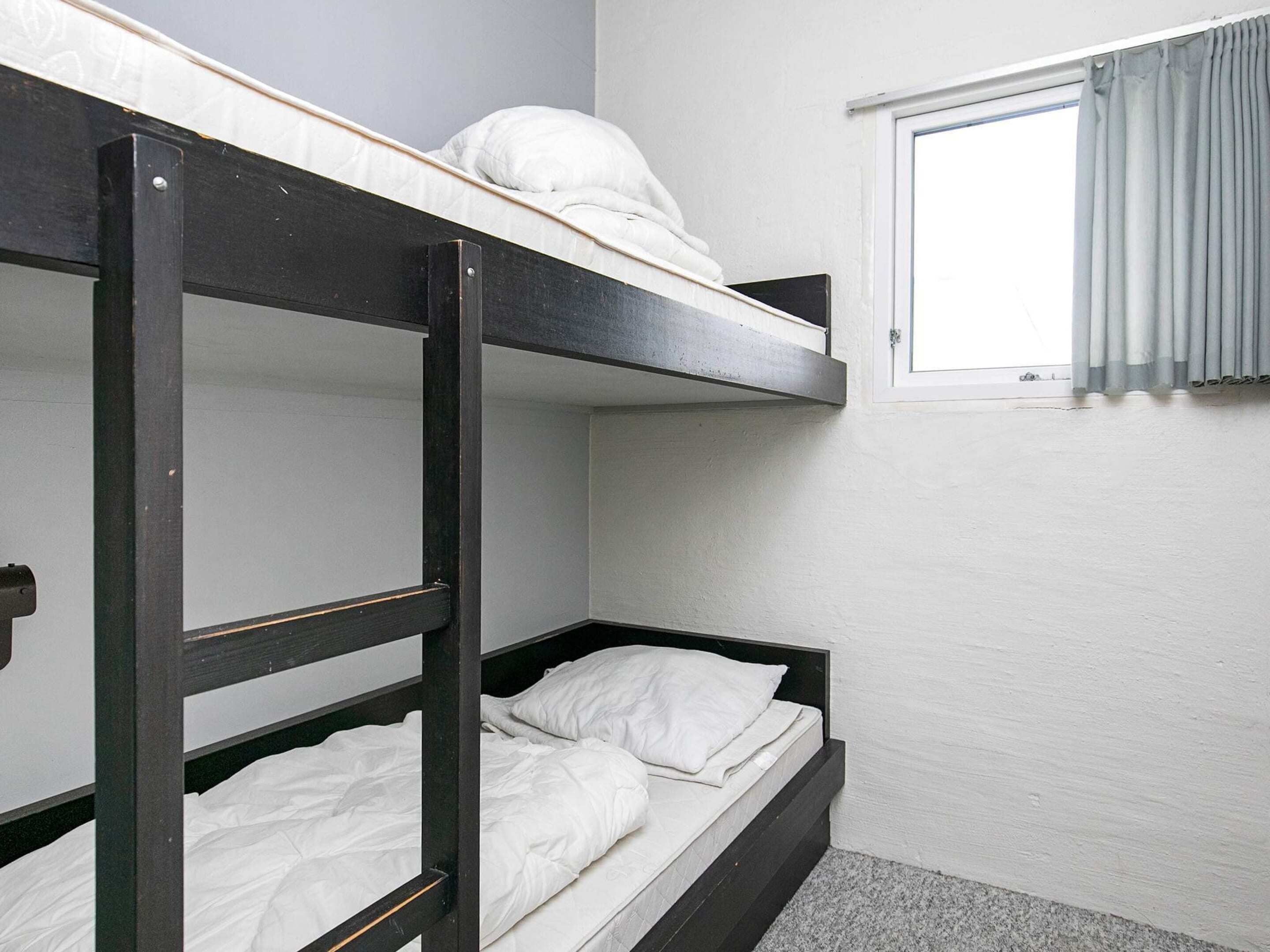 Quarto com beliche, janela e cortinas.