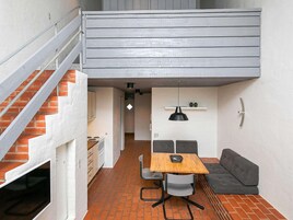 Um espaço compacto com cozinha, área de refeições e espaço para sentar, incluindo uma escada e um mezanino.