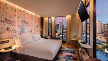 Quarto de hotel com uma cama grande, uma escrivaninha, uma cadeira, televisão e vista para a cidade.