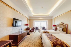 Quarto de hotel com duas camas, uma televisão, uma escrivaninha e uma cadeira.