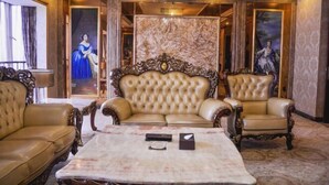 Um quarto luxuoso com um sofá estofado, duas poltronas e uma mesa de centro de mármore.