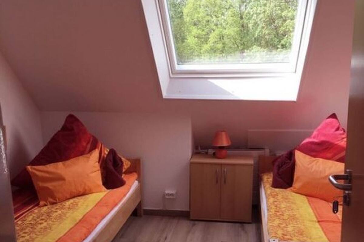 Acomodação compacta, com um quarto e duas camas, guarda-roupa de madeira e claraboia.