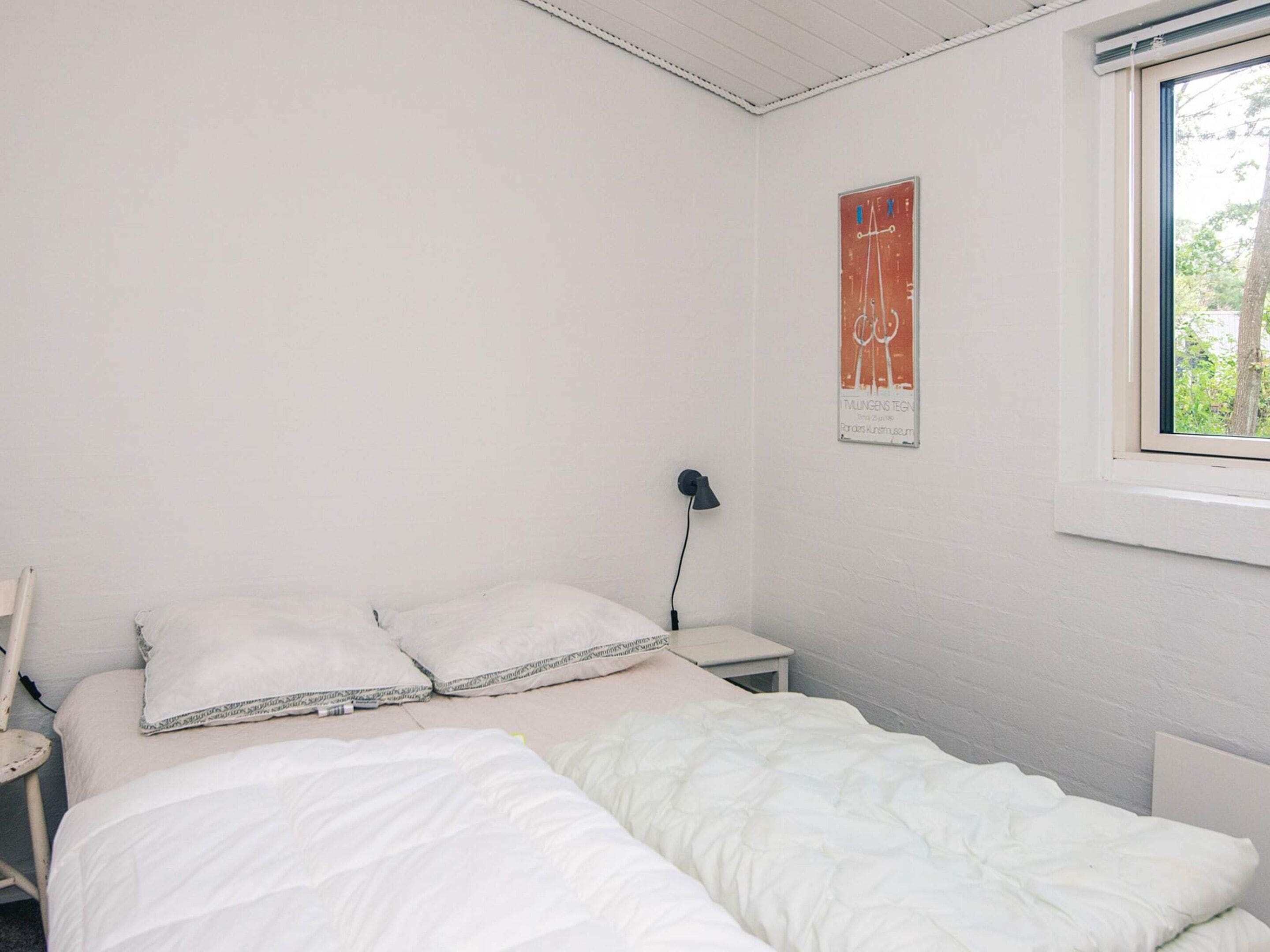 Quarto com cama, mesa de cabeceira, abajur e janela.