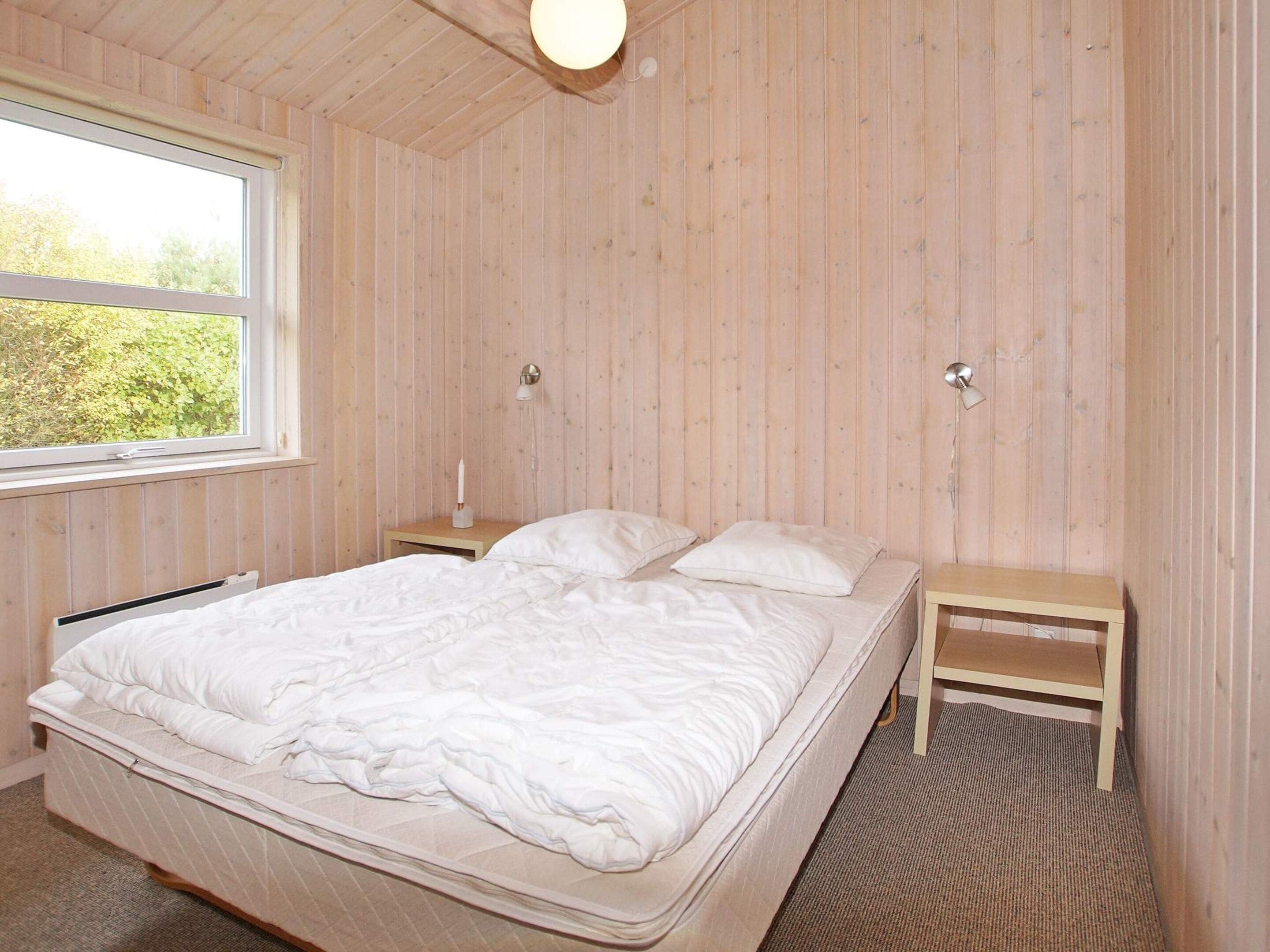 Quarto com cama, duas mesas de cabeceira, janela e ventilador de teto.