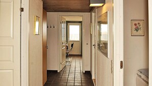 Um corredor com piso de azulejos, paredes brancas e portas que dão para outros cômodos.