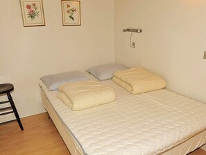Uma cama de solteiro com colchão acolchoado, duas almofadas e uma mesa de cabeceira com cadeira.