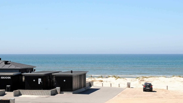 Um edifício à beira-mar chamado ISKIOSK, com área de estacionamento e vista para o oceano.