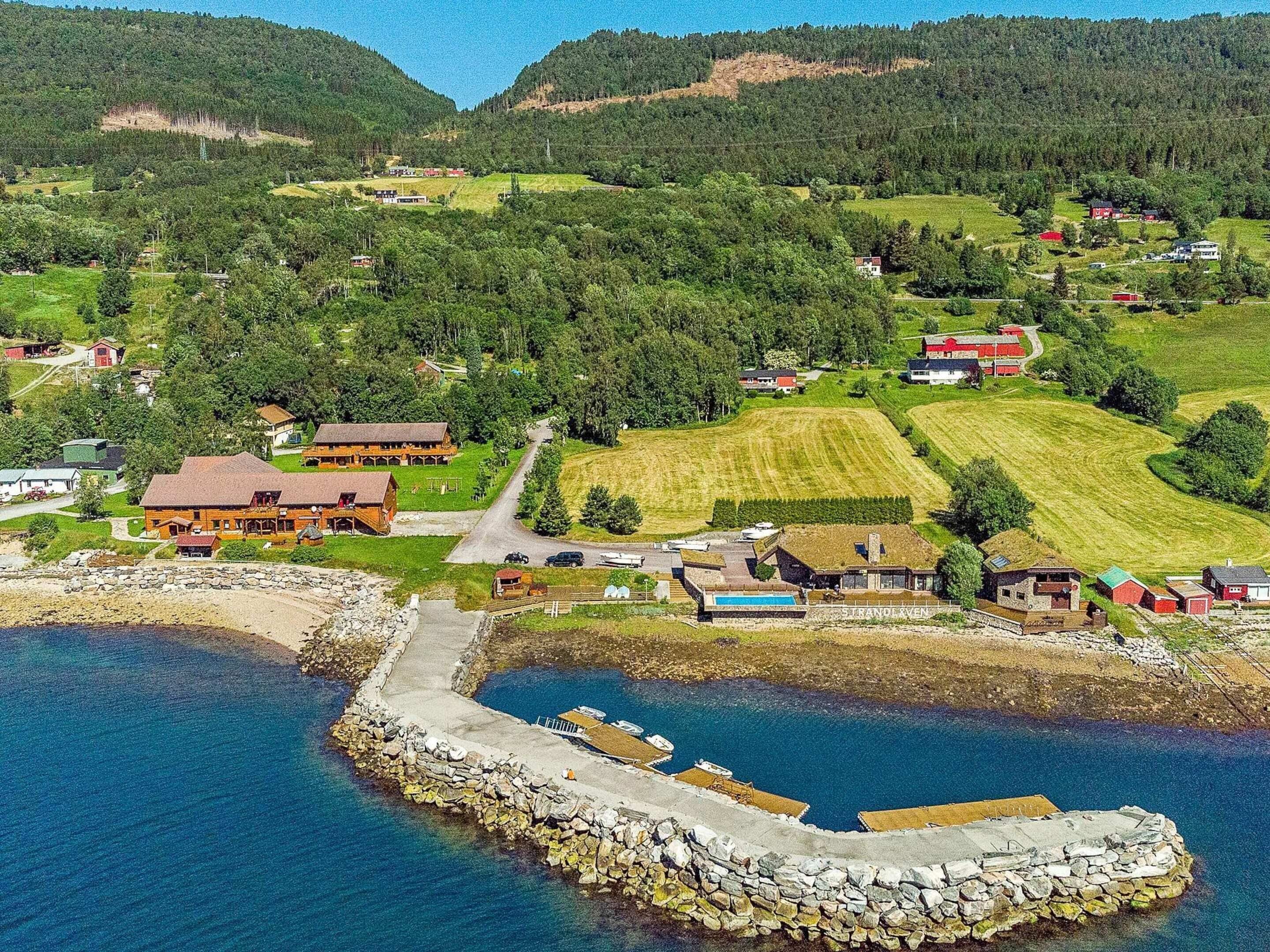 Vista aérea de uma vila costeira com casas, um cais e um paredão de pedra.
