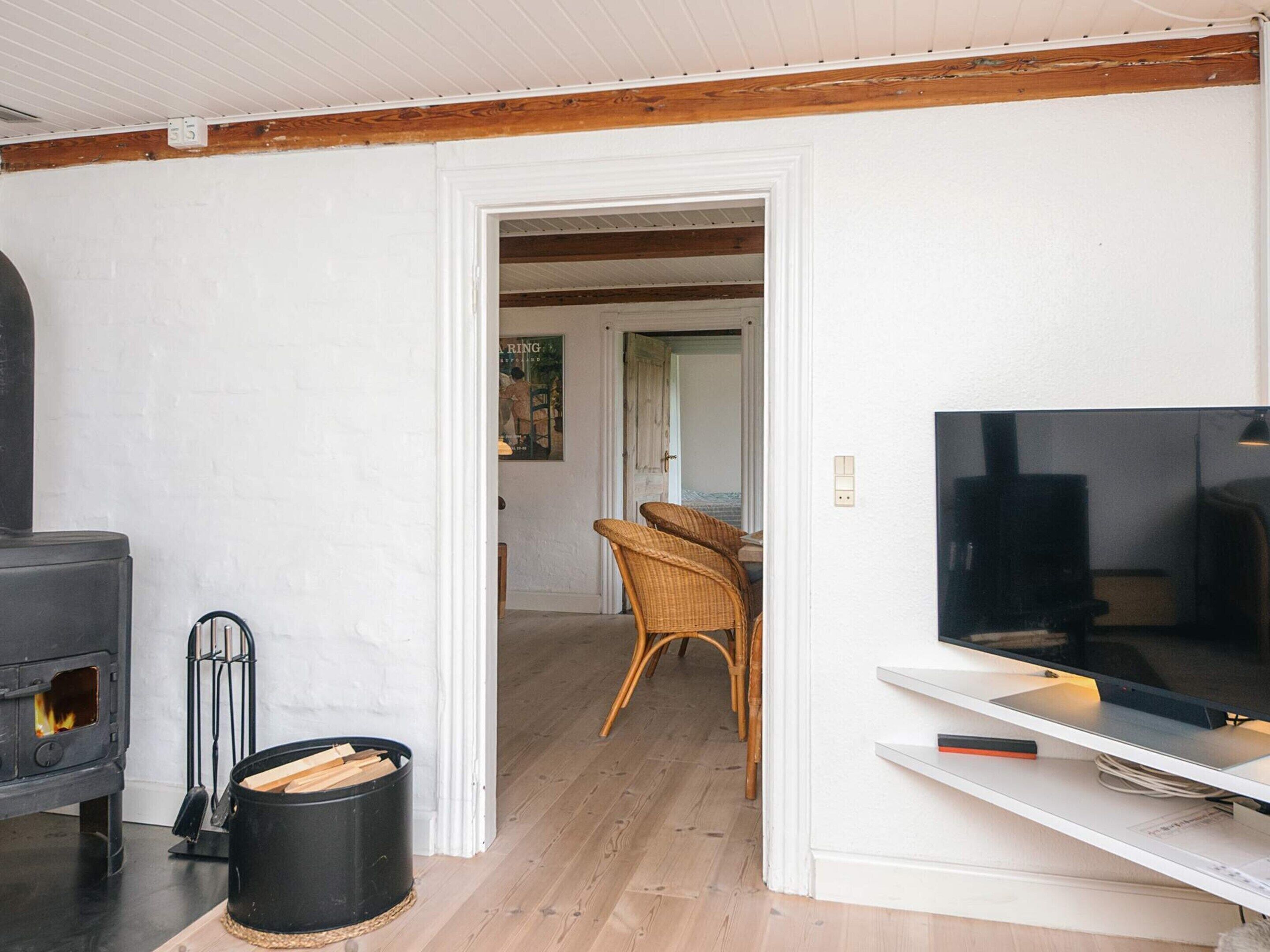 Quarto com televisão, lareira e área de jantar com cadeiras.