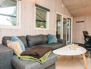 Uma sala de estar moderna com um sofá cinzento, uma mesa de centro branca e uma cadeira preta.