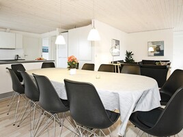 Uma sala de jantar moderna com uma mesa redonda, cadeiras pretas e iluminação pendente.
