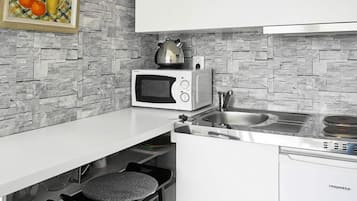 Cozinha compacta equipada com micro-ondas, chaleira e pia.