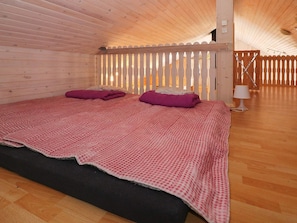 Quarto de cabana de madeira com cama, assoalho de madeira e cerca branca.