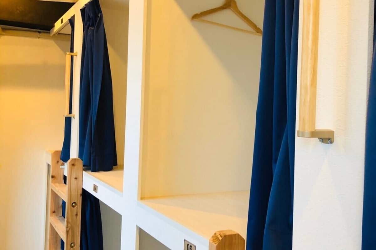 Quarto com beliches de madeira, paredes brancas e cortinas azul-escuro.
