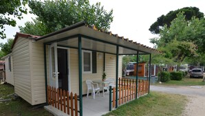 Uma casa móvel pequena, térrea, com varanda coberta e pátio cercado.