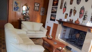 Uma sala de estar com sofá branco, mesa de centro de madeira e lareira.