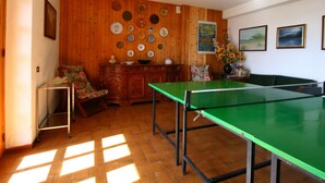 Um quarto com mesa de pingue-pongue, paredes de madeira e piso de azulejos.