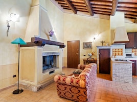 Uma sala de estar aconchegante com lareira, um sofá, uma luminária e uma área de cozinha com micro-ondas e fogão a gás.