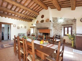 Uma área de refeições com mesa e cadeiras de madeira, lareira de pedra e teto rústico.