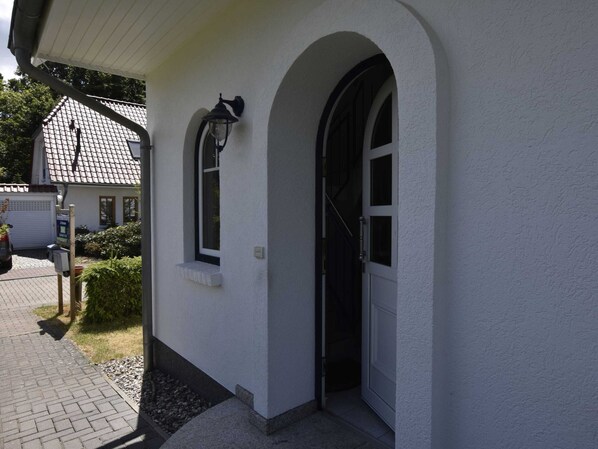 Um edifício com fachada branca, porta preta e janela com luminária.