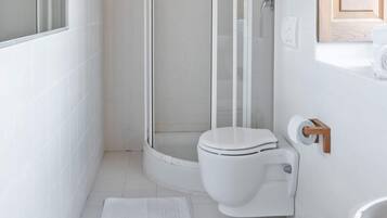 Uma casa de banho moderna com sanita, chuveiro e lavatório.