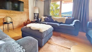 Uma sala de estar acolhedora com um amplo sofá modular, lareira e vista para o exterior.
