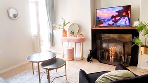 Uma sala de estar com televisão, sofá, mesa pequena e uma cadeira.