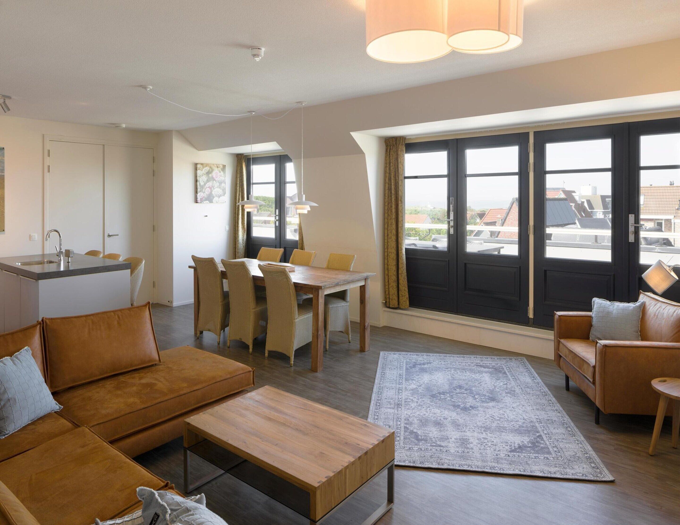 Uma sala de estar moderna com sofá, mesa de centro e área de jantar.