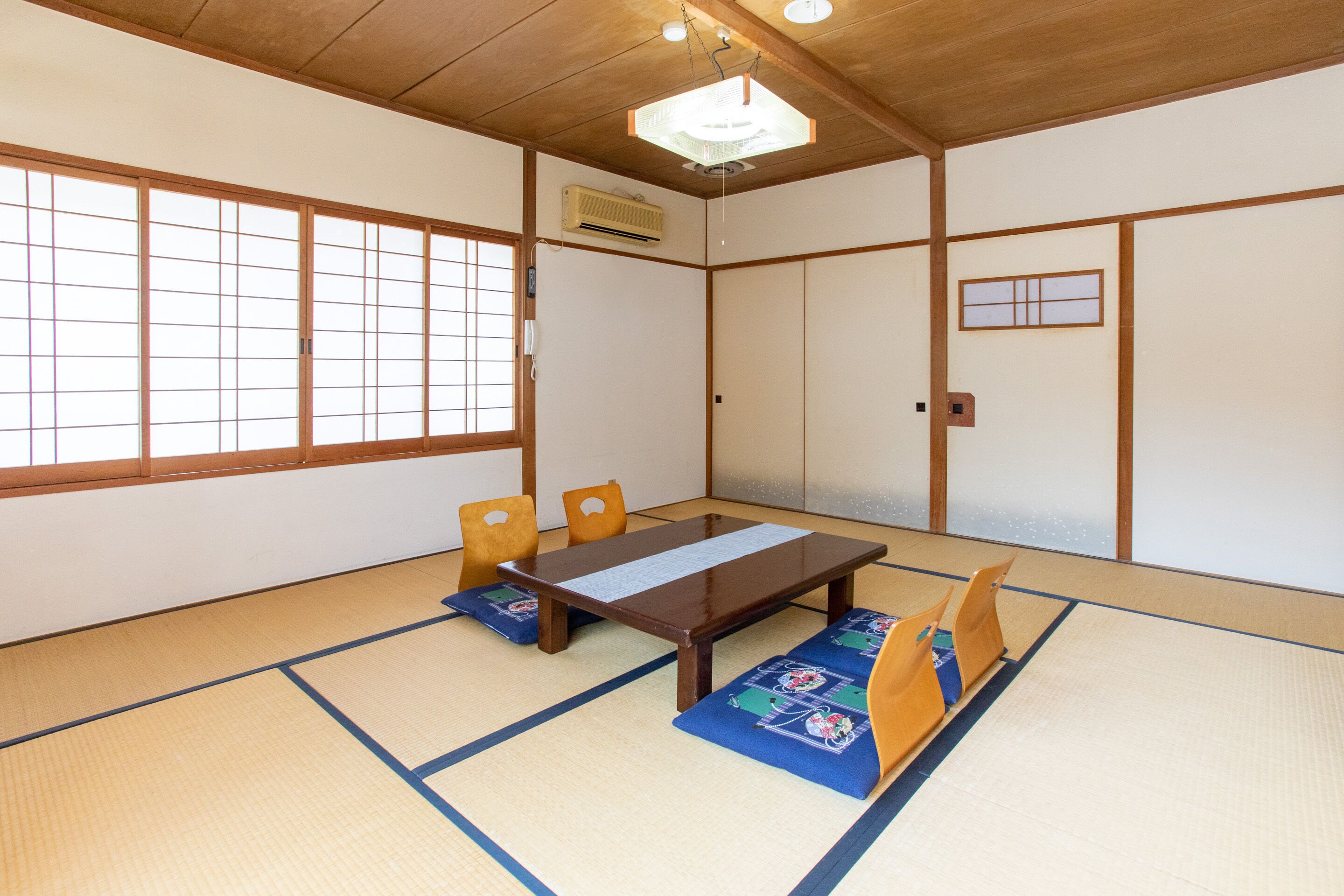 Um quarto japonês tradicional com piso de tatame, uma mesa de madeira baixa e quatro tatames com almofadas.