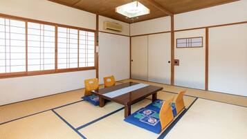Um quarto japonês tradicional com piso de tatame, uma mesa de madeira baixa e quatro tatames com almofadas.